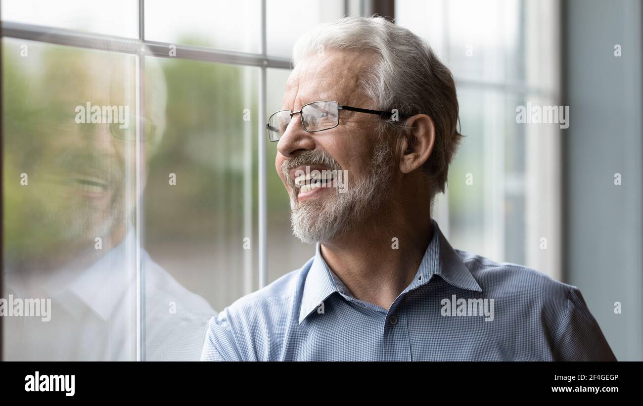 Healthy aged male stand by window laugh watch something outside Stock ...