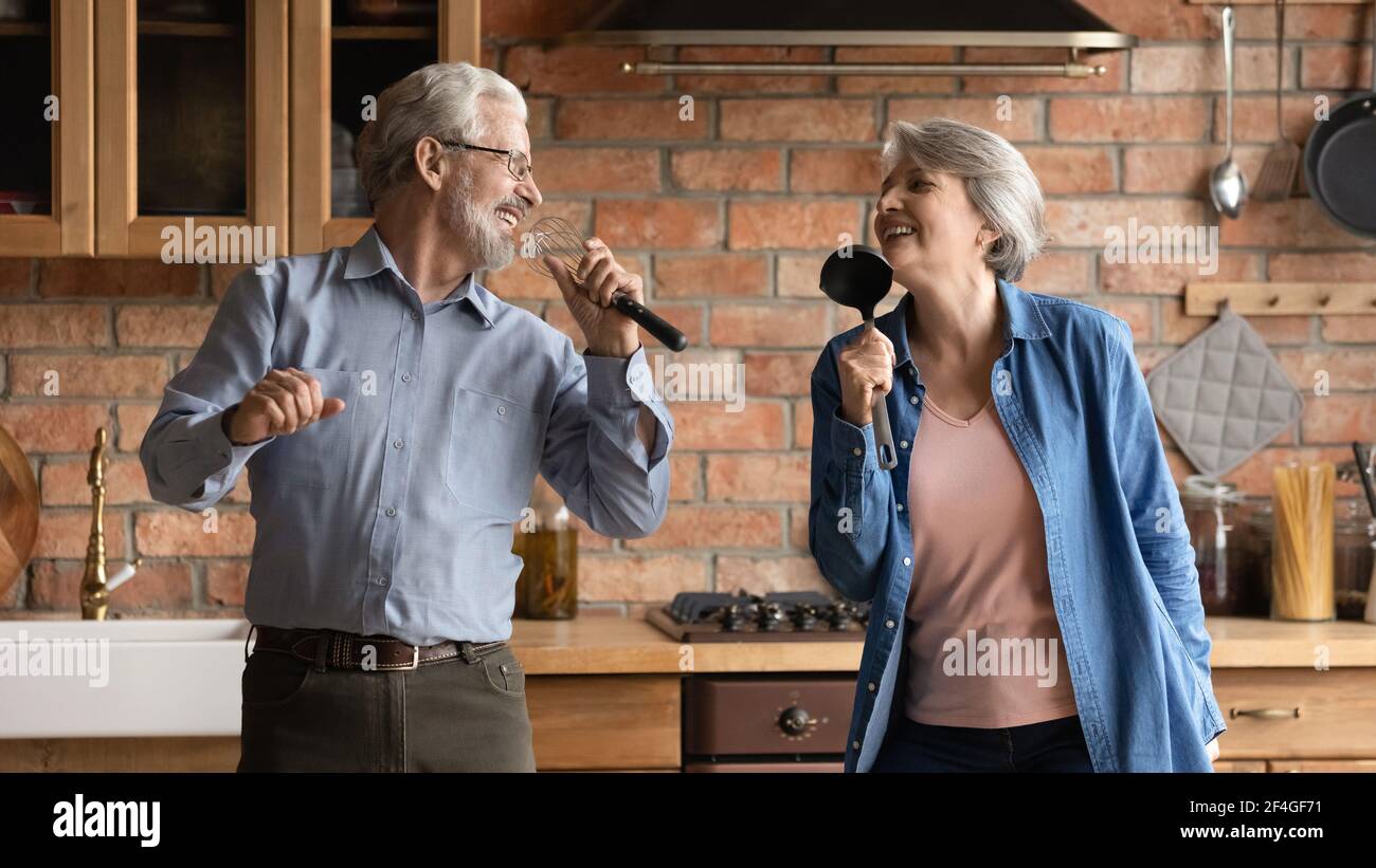 Overjoyed older senior couple having fun sing songs at kitchen Stock ...
