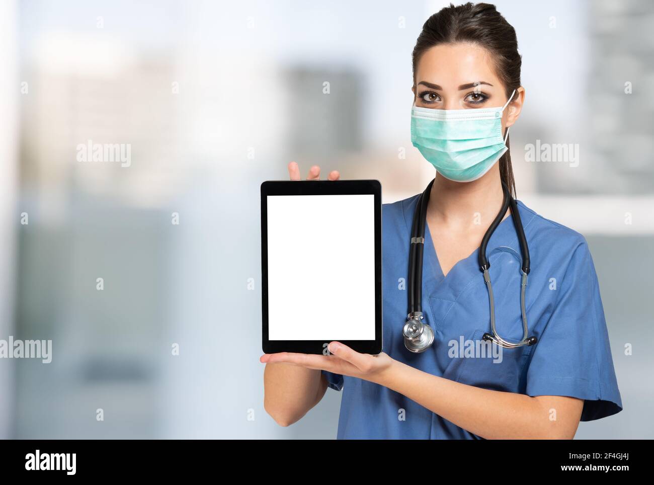 Masked nurse doctor showing a tablet with a white screen Stock Photo ...