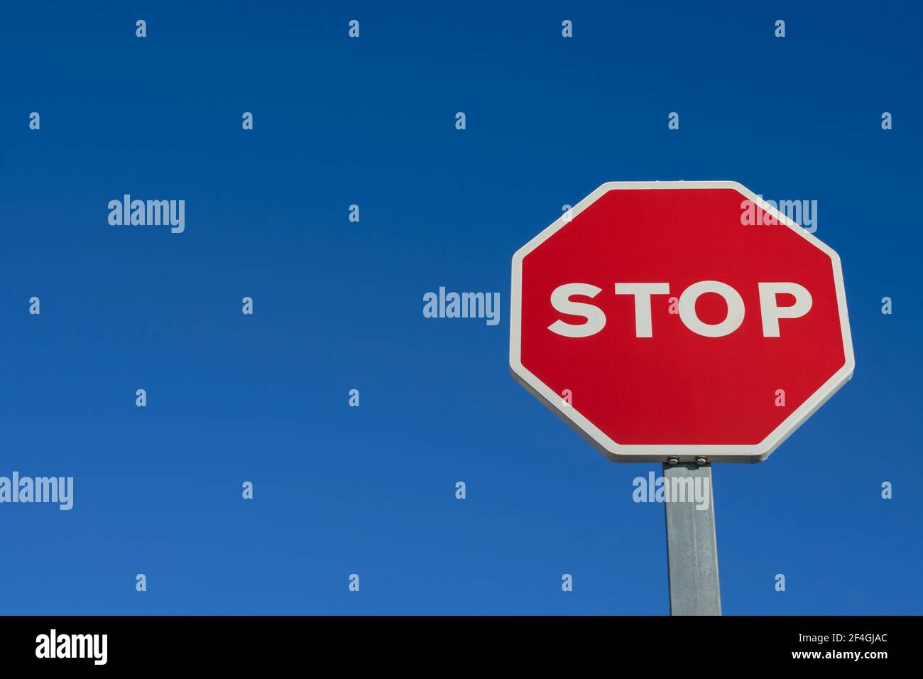 Vertical traffic stop sign, in red and white tones, on blue background ...