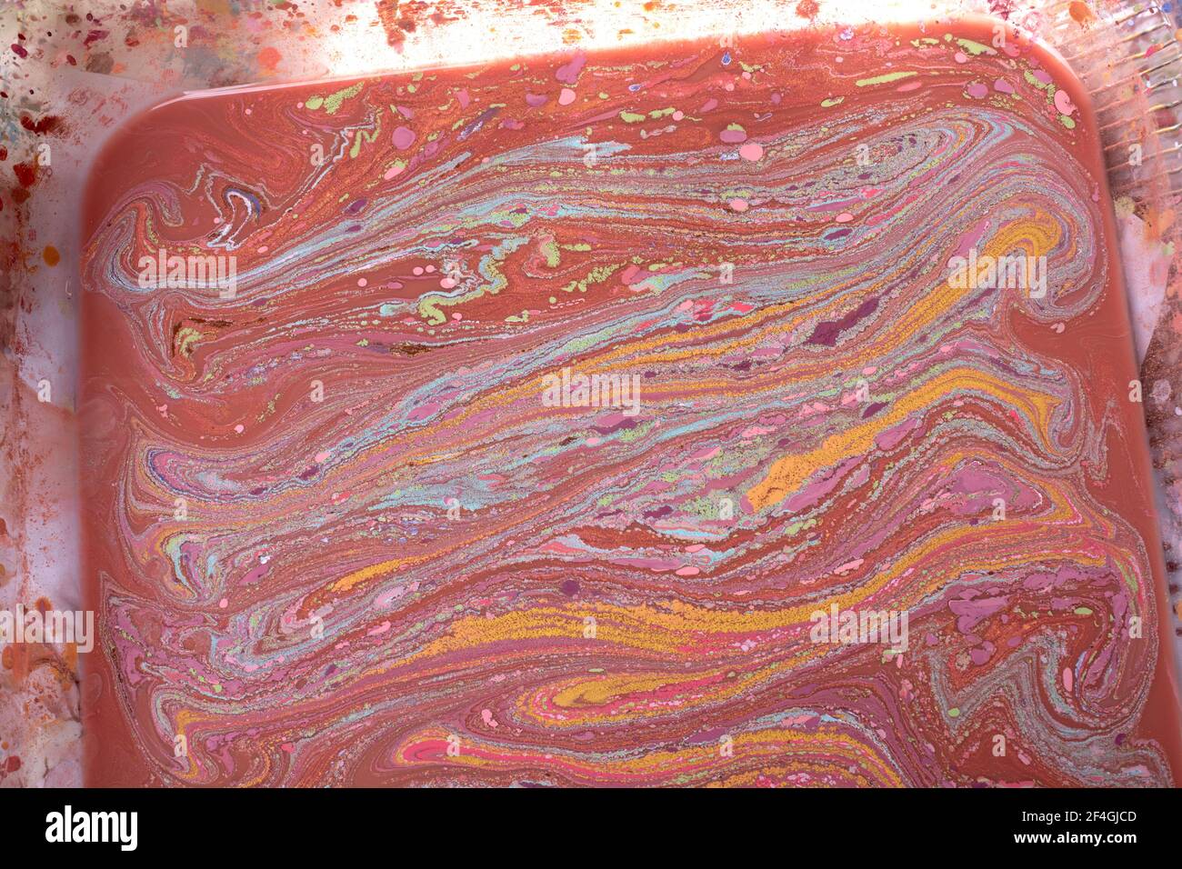 A top view of mixed oil paints in a plastic container under the ligh ...