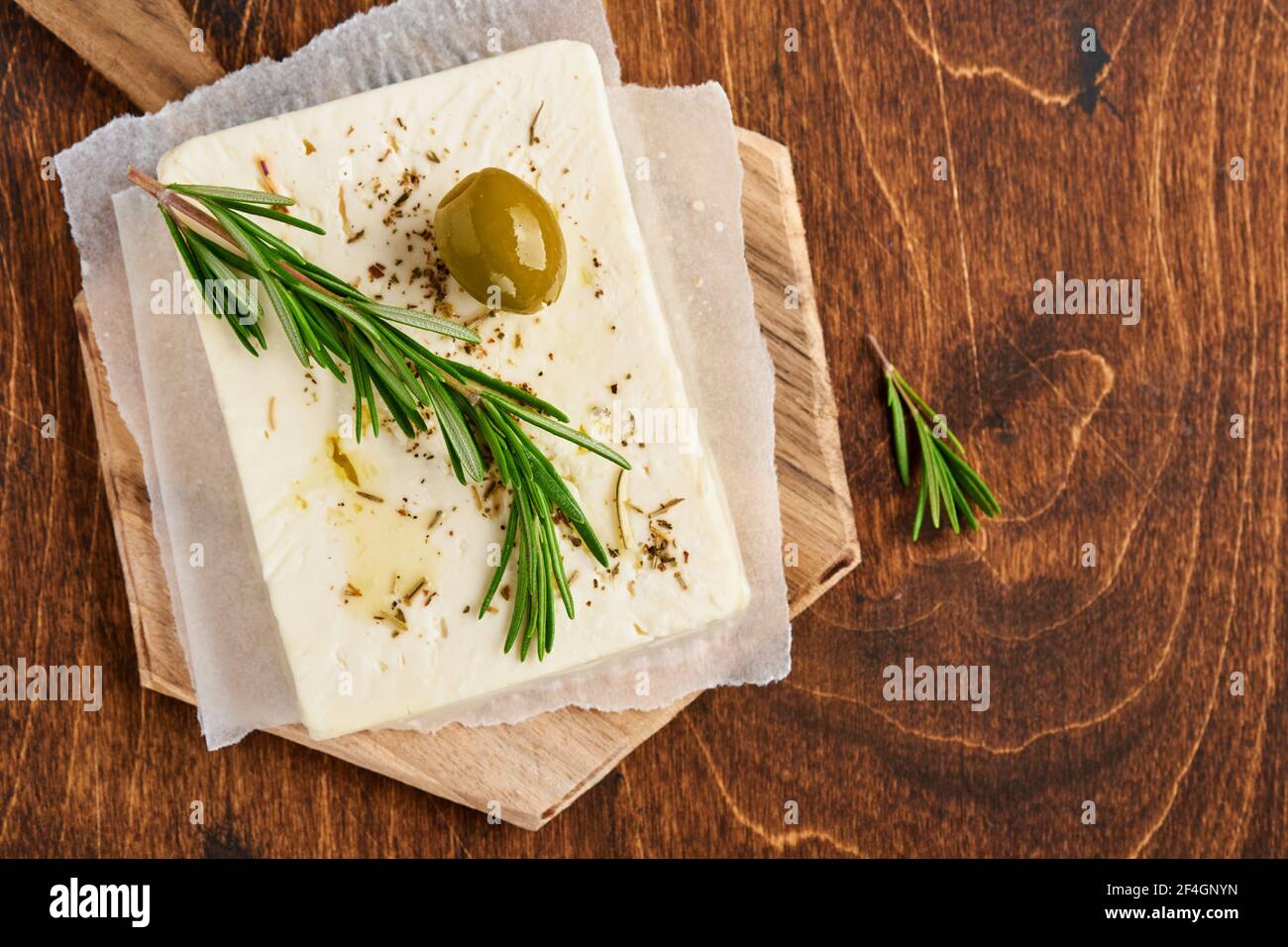 Cheese feta with rosemary, herbs, olives and olive oil on wooden ...
