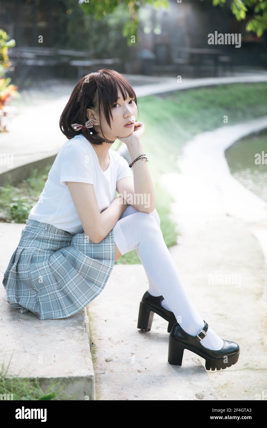 portrait of asian girl with white shirt and skirt sitting in outdoor ...