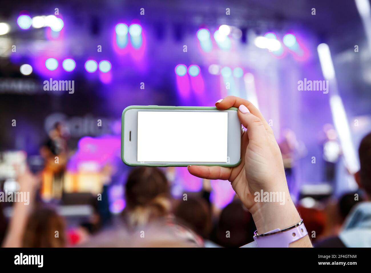 Hands holding a mobile smartphone on a live concert with a blank white ...