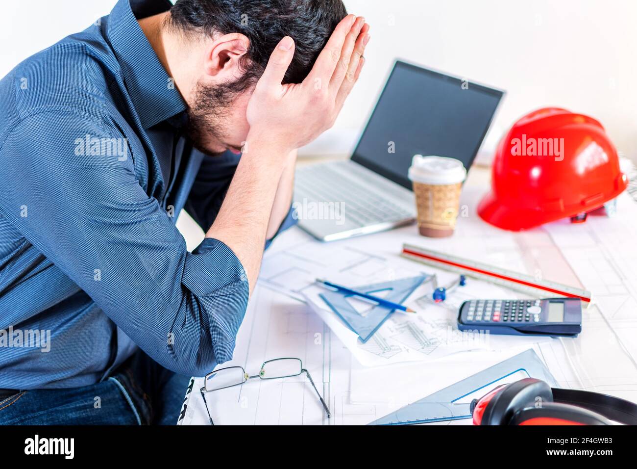 A tired frustrated Caucasian engineer working at an office with a ...
