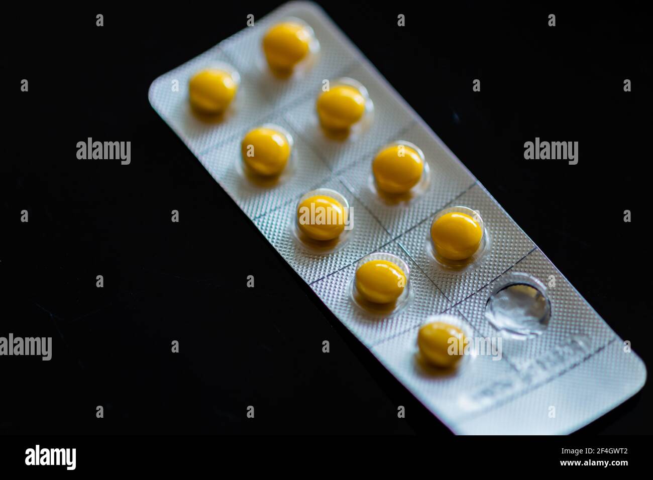 Yellow tablets in blister pack on black background Stock Photo - Alamy