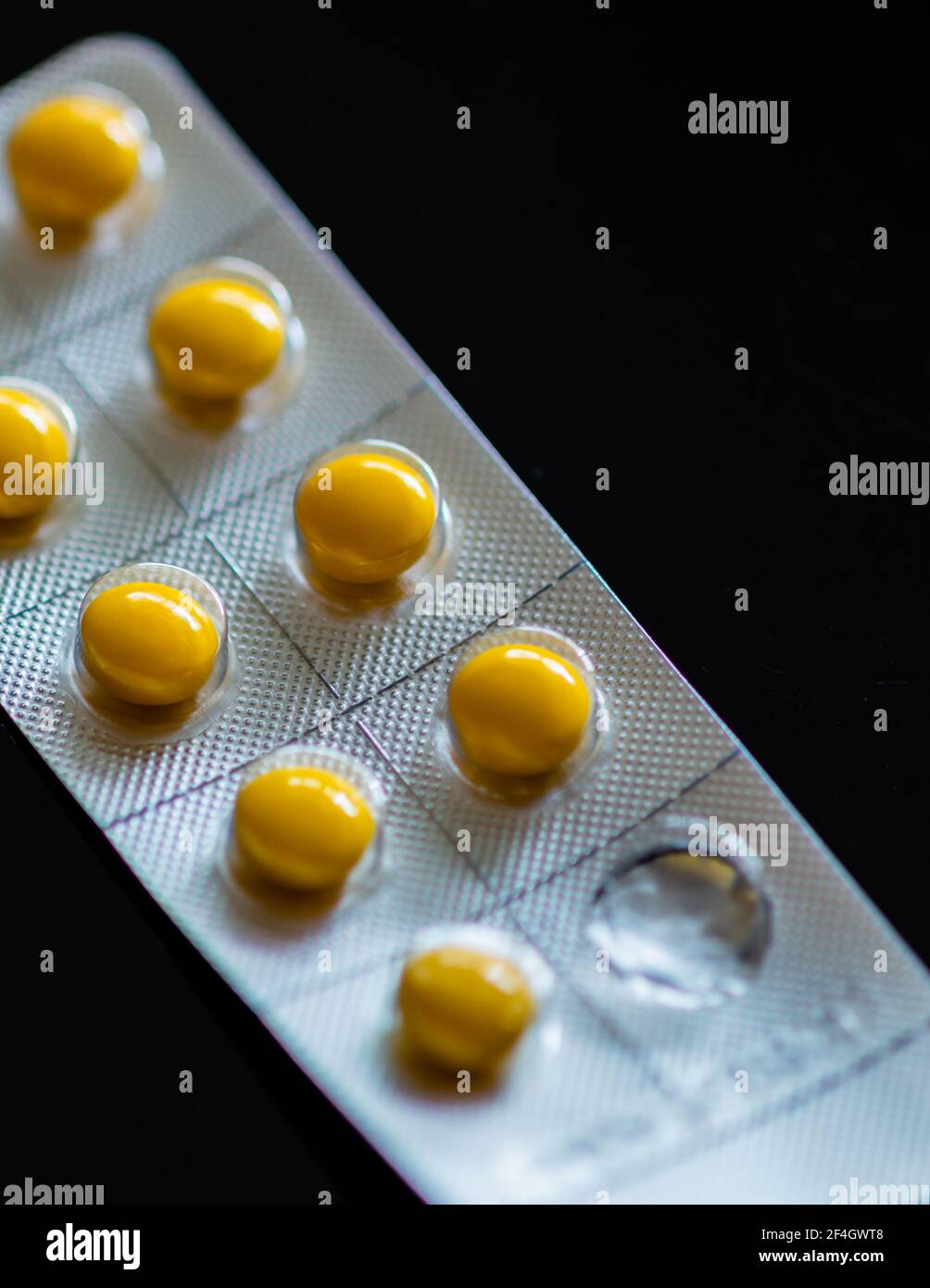 Yellow tablets in blister pack on black background Stock Photo - Alamy