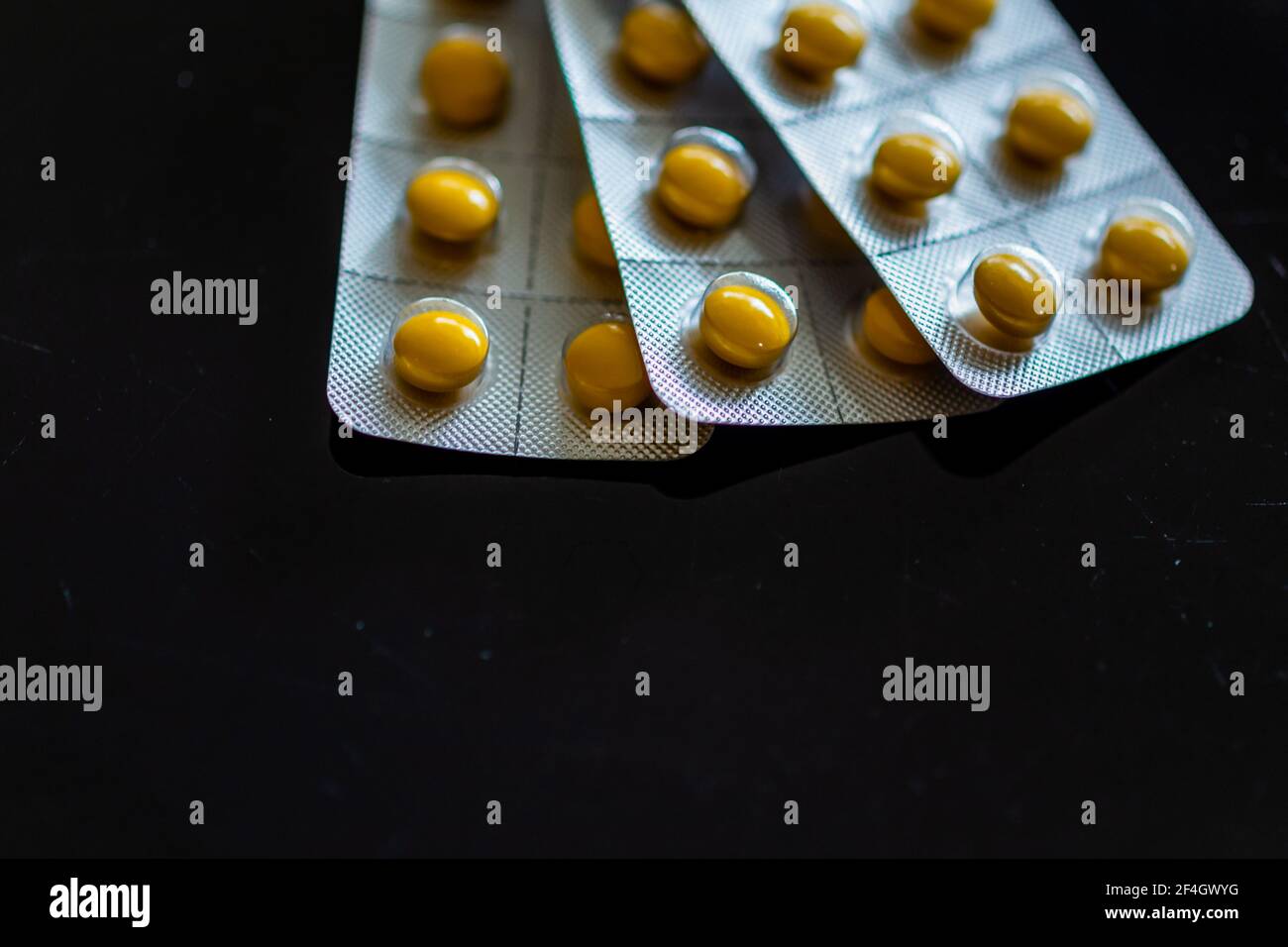 Yellow tablets in blister pack on black background Stock Photo - Alamy