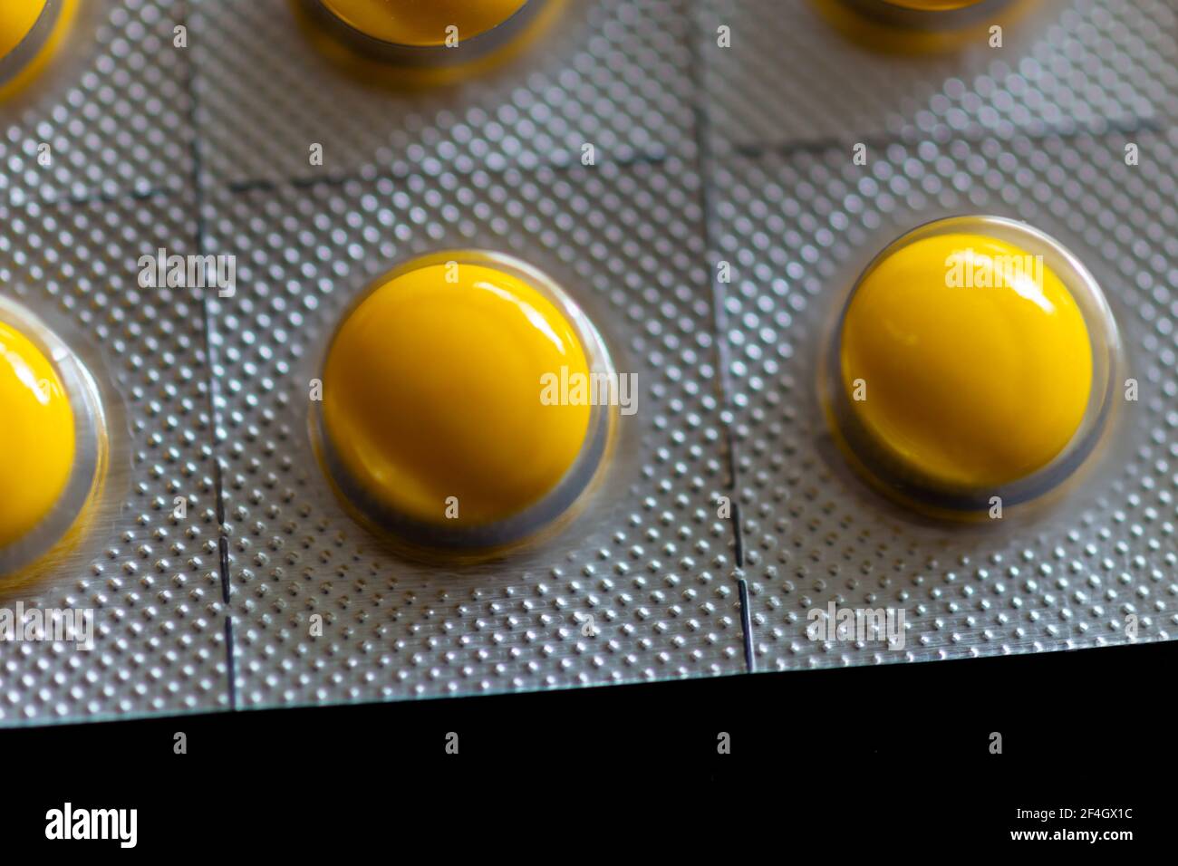 Yellow tablets in blister pack on black background Stock Photo - Alamy