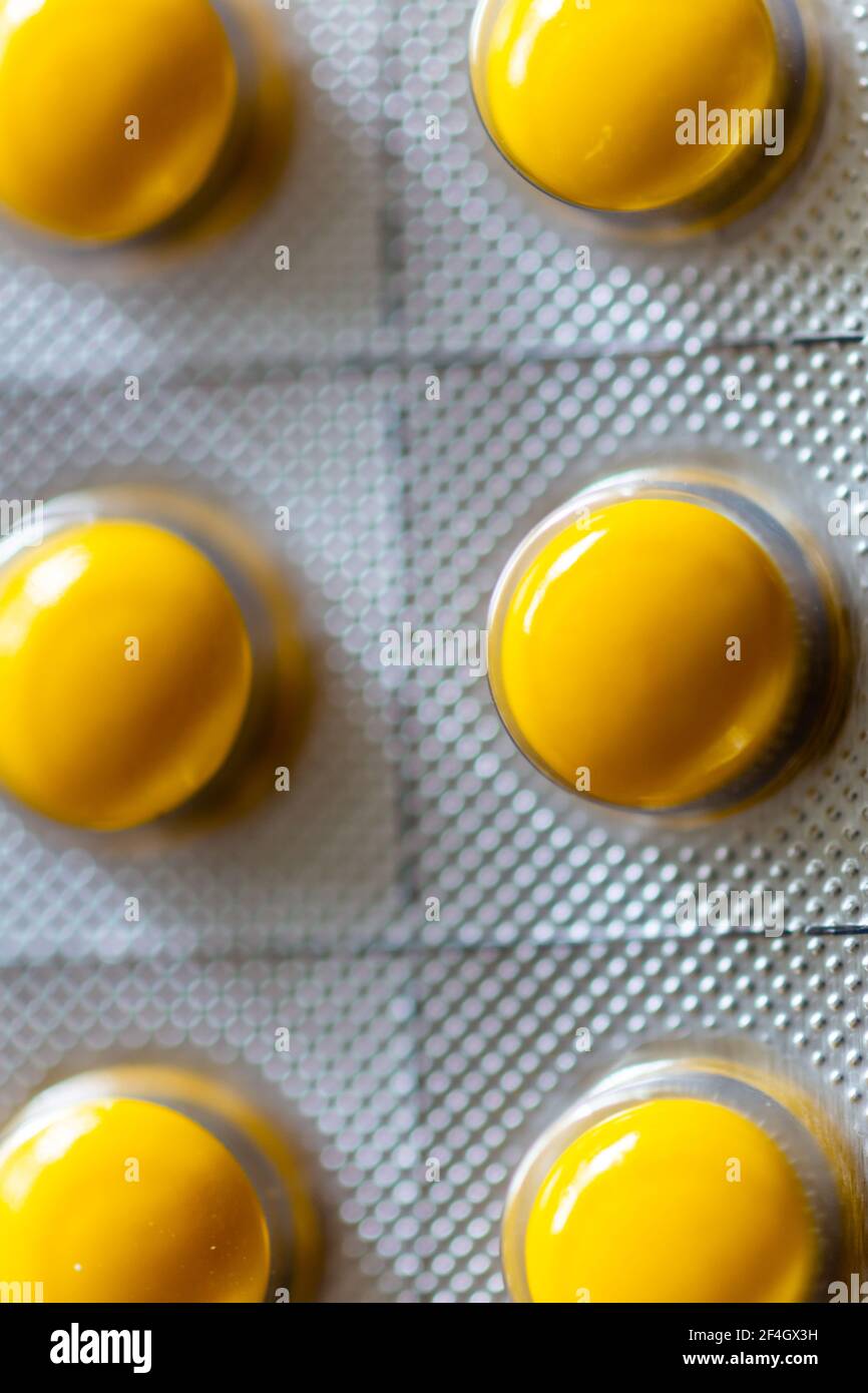 Yellow tablets in blister pack on black background Stock Photo - Alamy