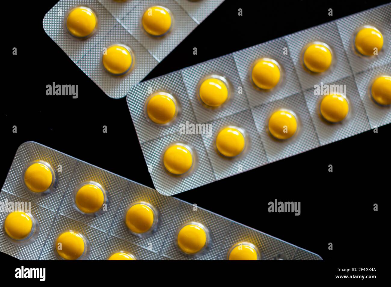 Yellow tablets in blister pack on black background Stock Photo - Alamy