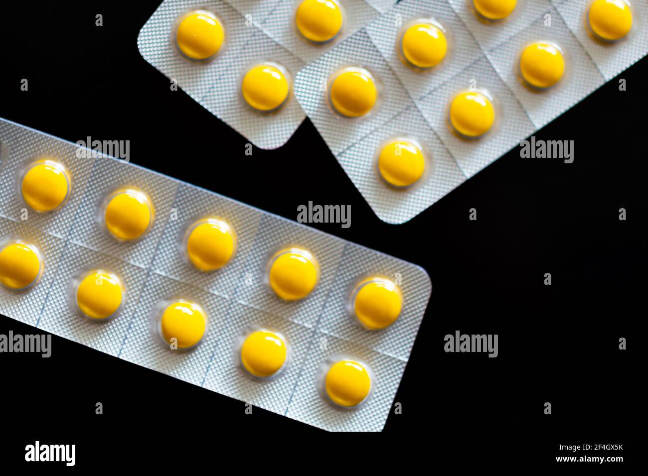 Yellow tablets in blister pack on black background Stock Photo - Alamy