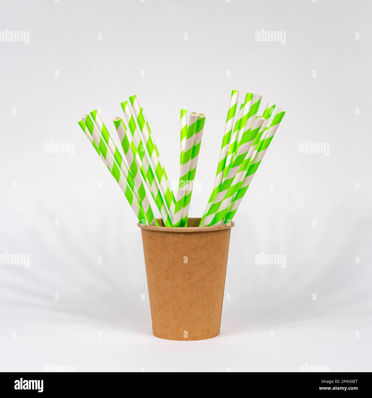 White and green paper drinking straws in a brown disposable paper cup ...
