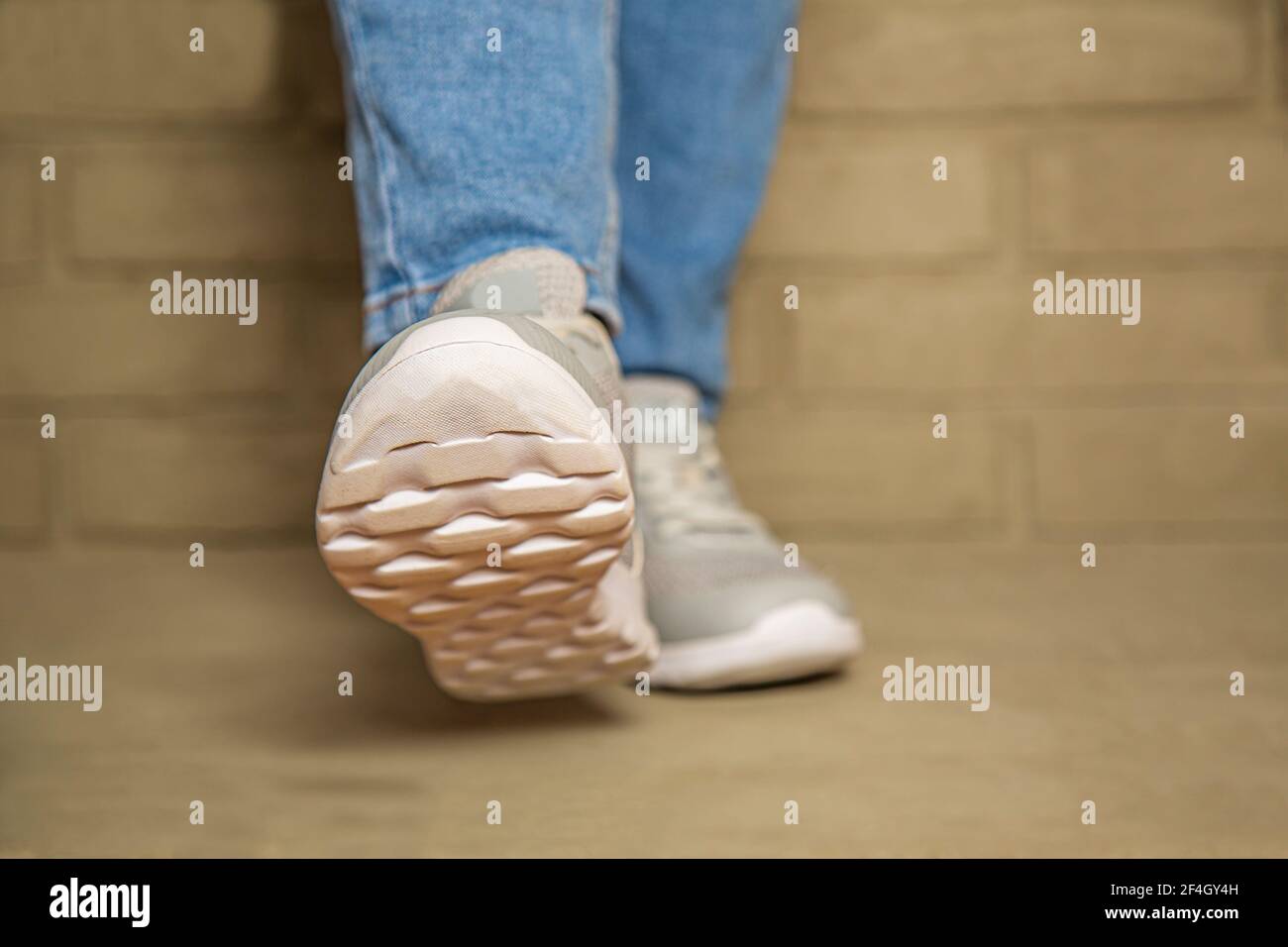 The woman jeans and sneaker shoes walking on the road. View from the ...