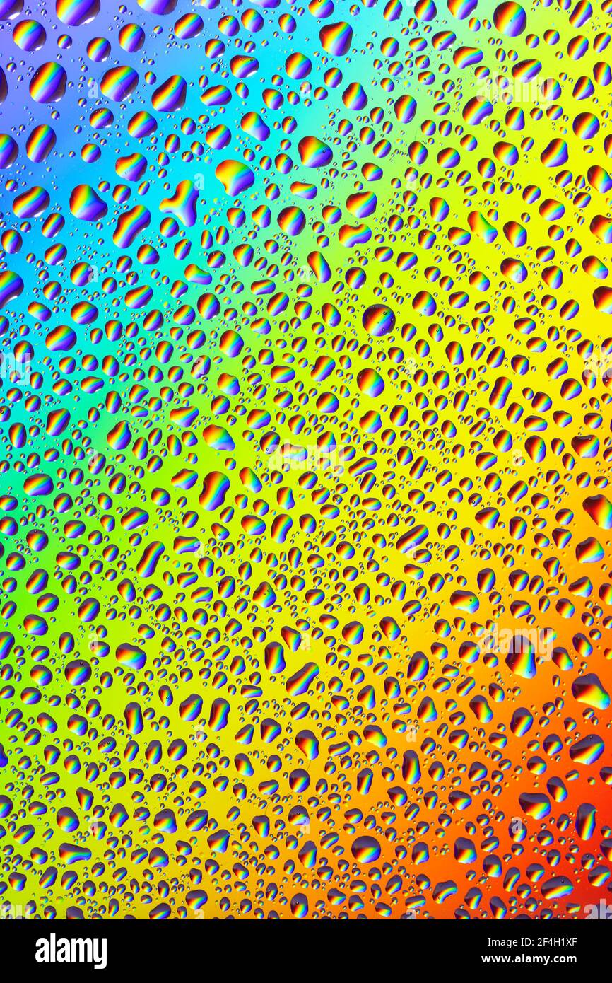 Water drops on a bright rainbow background and the reflection of the ...