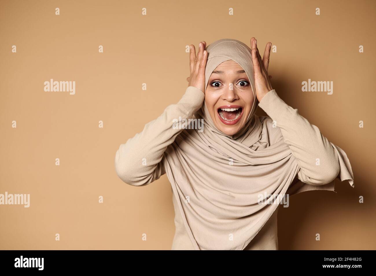 A charming muslim woman in hijab and strict clothes holds her head with ...