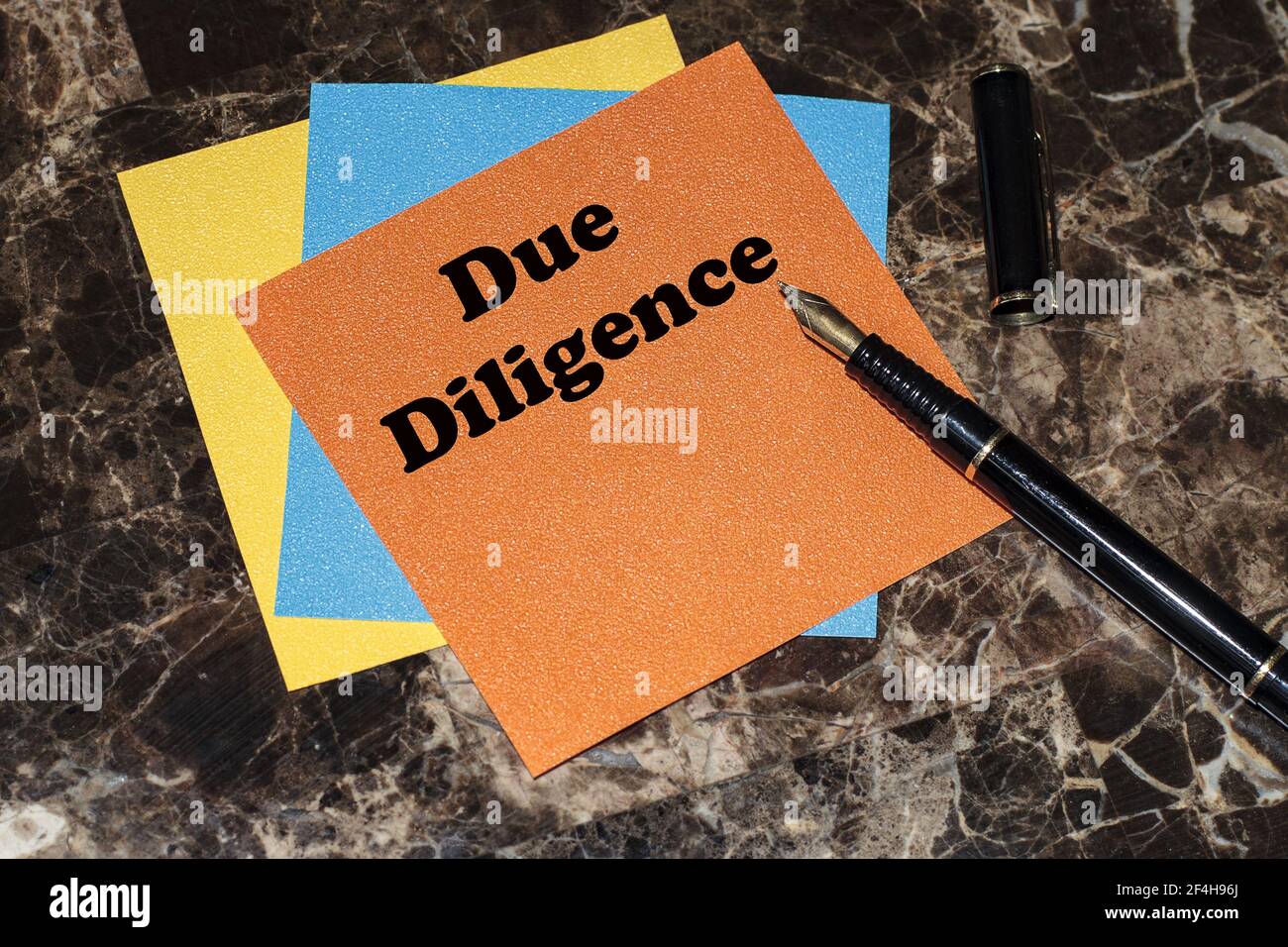 DUE DILIGENCE. Text on a stack of multi-colored memo stickers lying ...