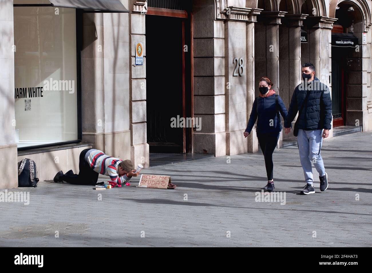 A couple walking past a man begging in the street Stock Photo - Alamy