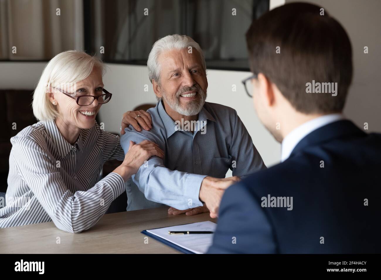 Smiling older couple clients handshake relator at meeting Stock Photo ...