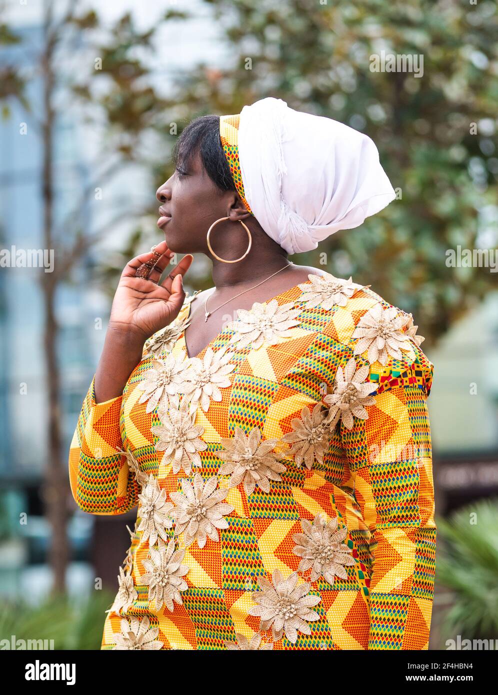 Side view of young African female in bright wear with floral ornament ...