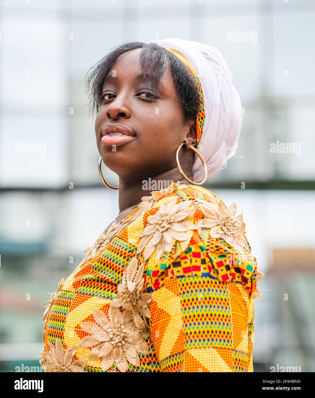 Side view of young African female in bright wear with floral ornament ...