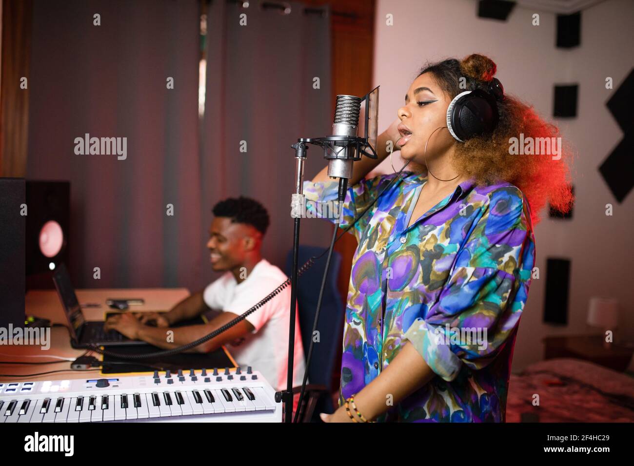 Side view of young African American female vocalist in headphones ...