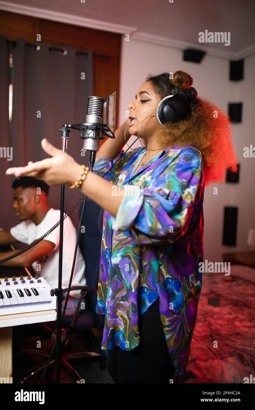 Side view of young African American female vocalist in headphones ...