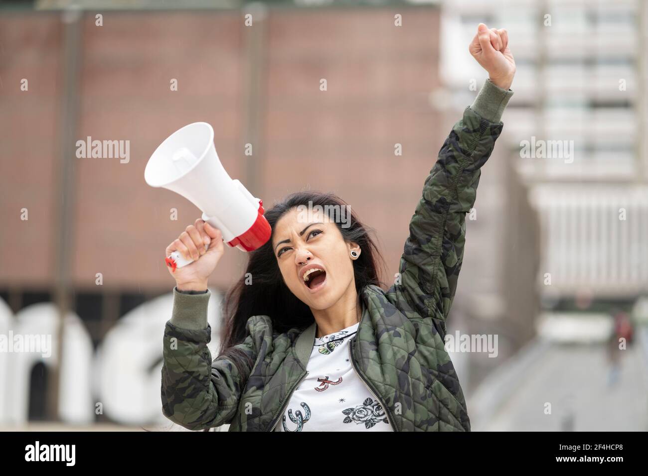 Low angle of Asian Woman with megaphone raising arm and screaming ...