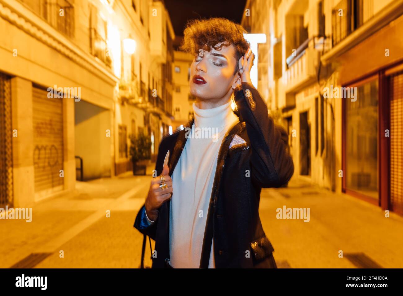 Young trendy transgender male standing on urban pavement with eyes ...