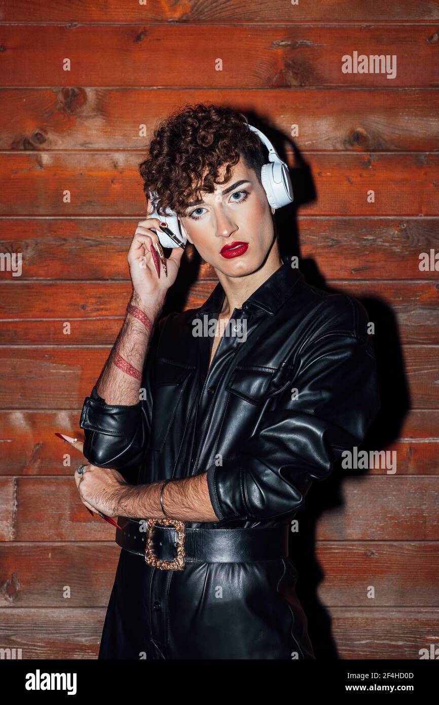 Young transgender male in leather jacket listening to music from ...
