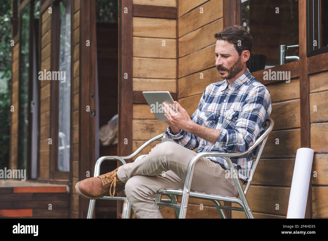 Side view of busy male architect sitting on chair on terrace with ...