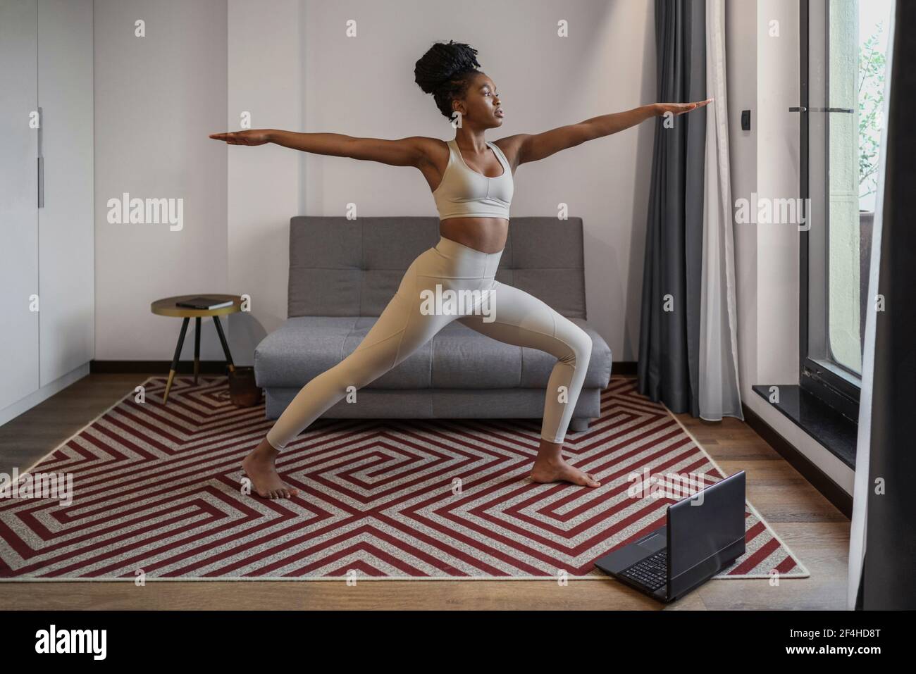 Full body of concentrated young black female in activewear watching ...