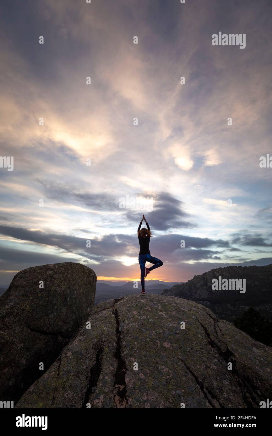 Back view of unrecognizable female standing on top of rocky mountain ...