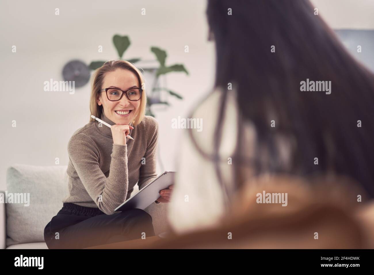 Cheerful female counselor listening to anonymous client while helping ...