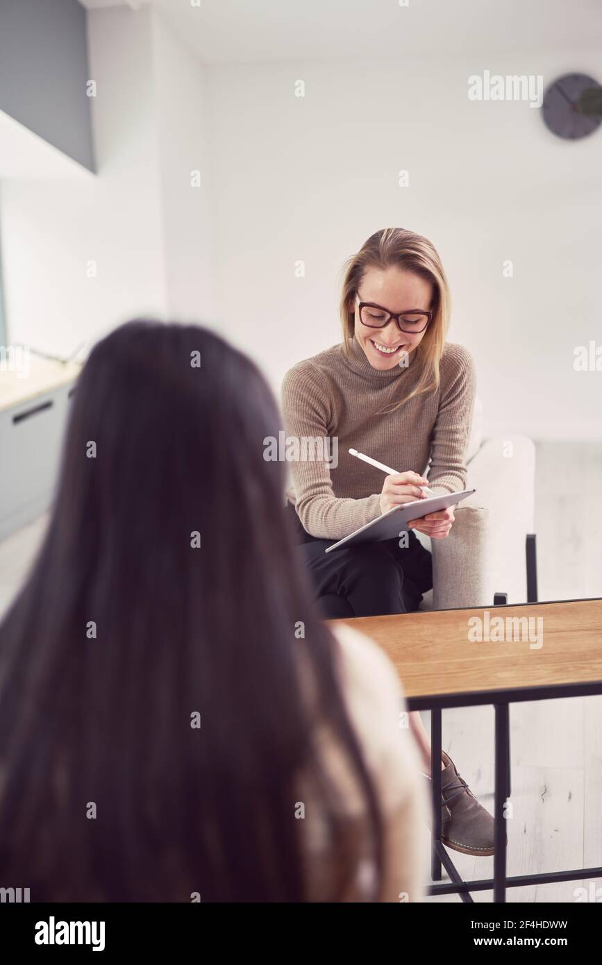 Cheerful female counselor listening to anonymous client while helping ...