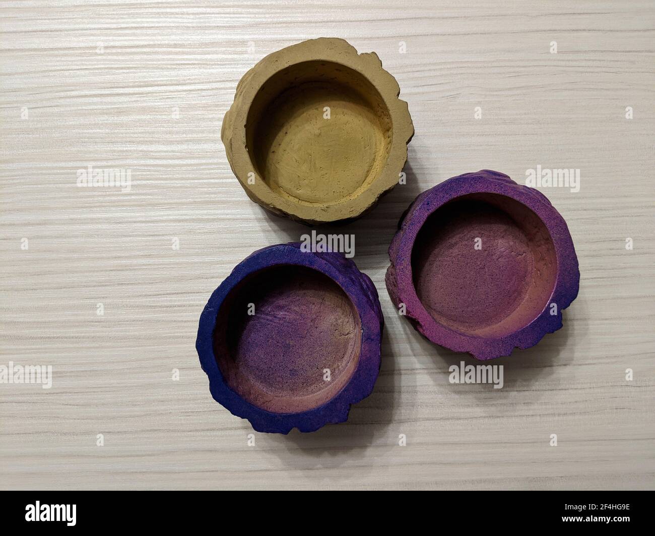 Three colored concrete pots isolated on light wooden background from a ...