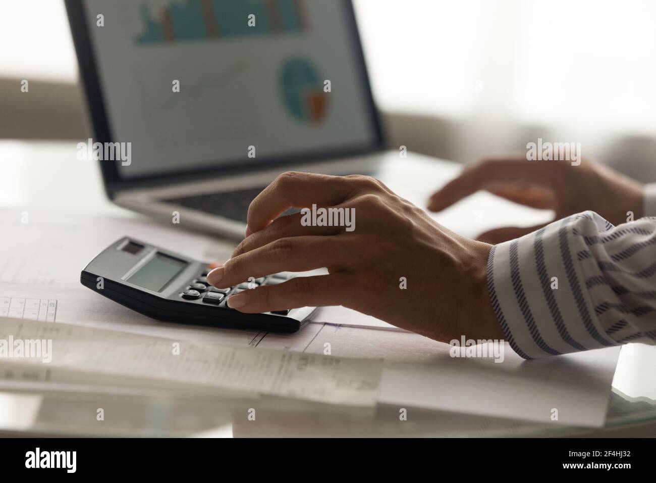 Close up businesswoman calculating company expenses, using laptop and ...