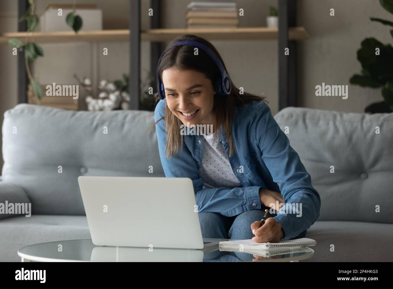 Close Up Smiling Woman Wearing Headphones Using Laptop Taking Notes