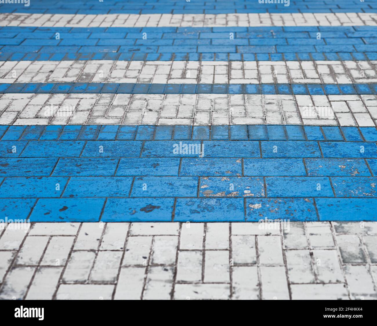 detail of a side view of a blue and white crosswalk on a cobblestone ...