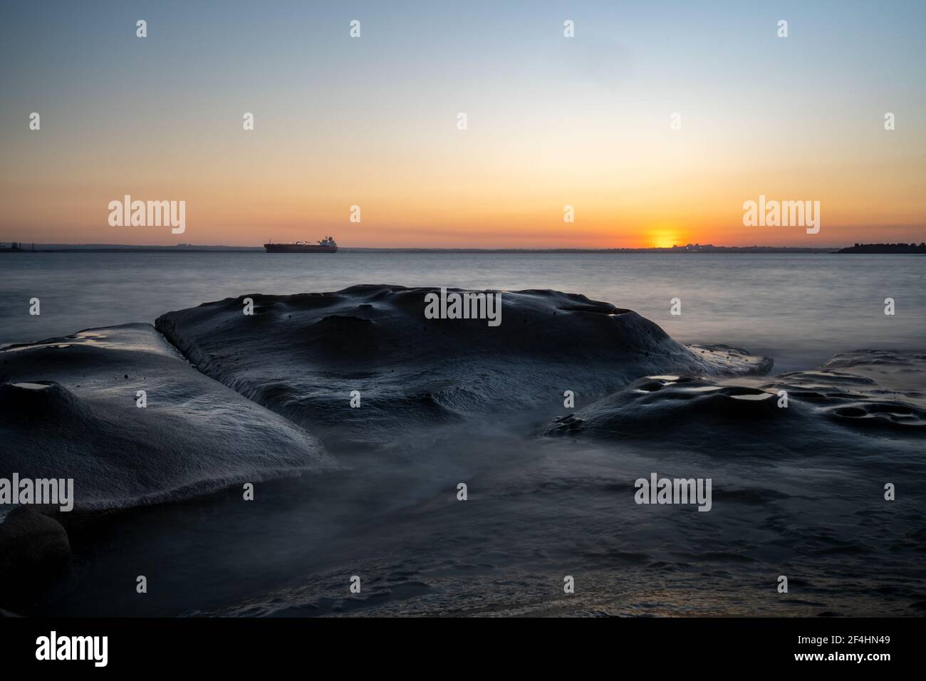 Orange sun sinking in the ocean during sunset Stock Photo - Alamy