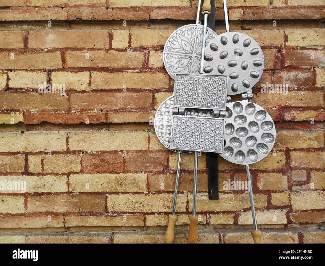A view of waffle molders hanging against a brick wall in Abruzzo, Italy ...