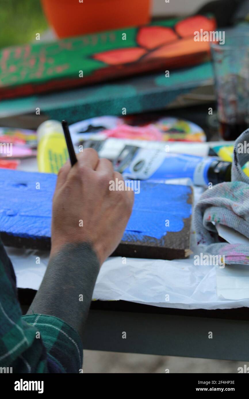 A closeup shot of hand painting a wooden board in blue color with a ...