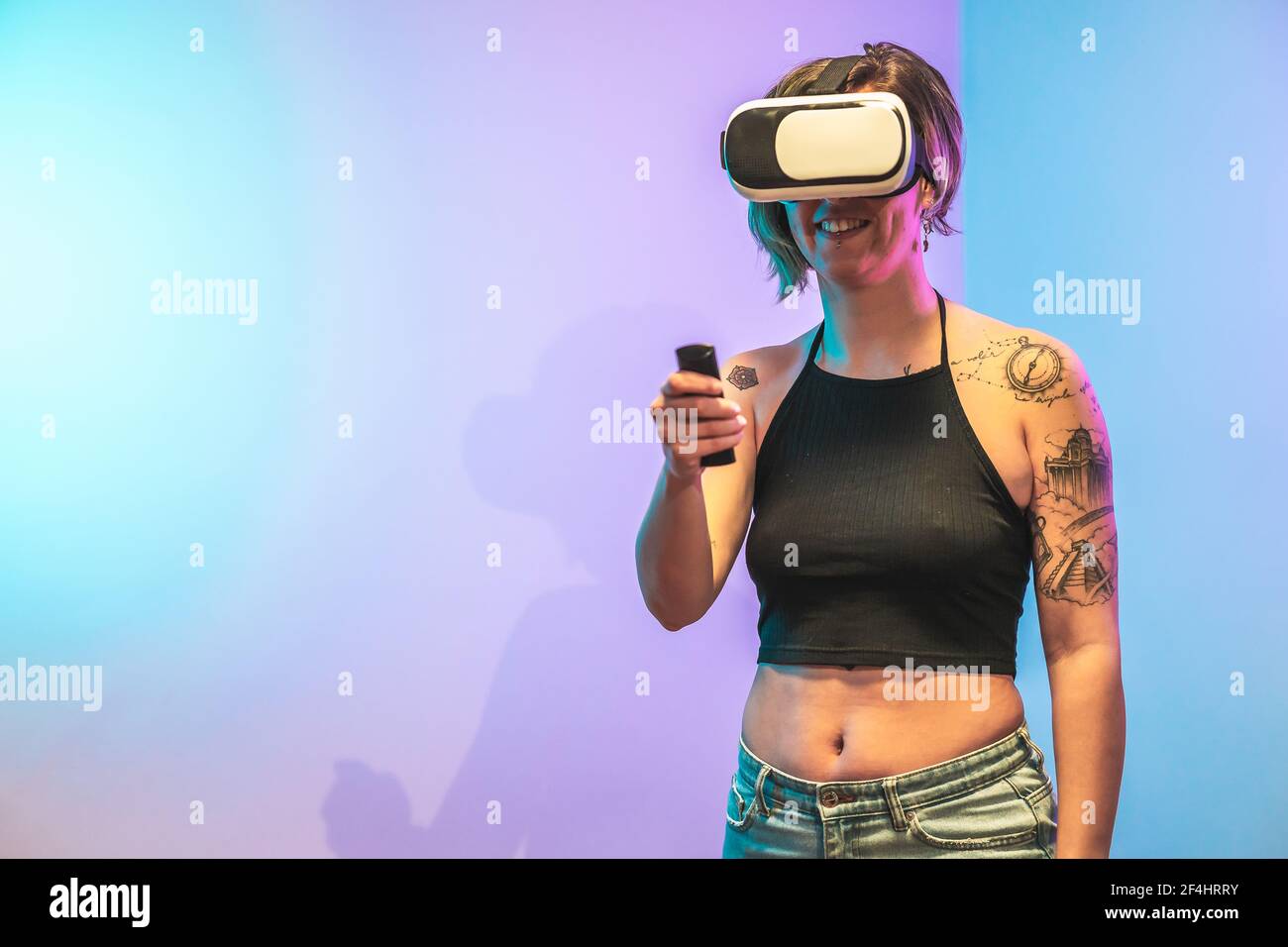 A portrait of a young happy Spanish woman with tattoos playing games on ...