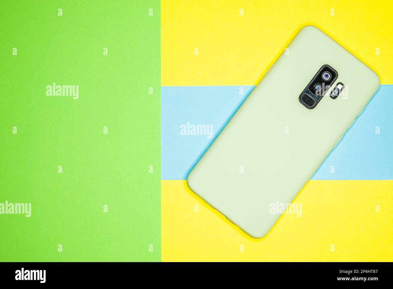 A modern light green mobile phone on a colorful background with a copy ...