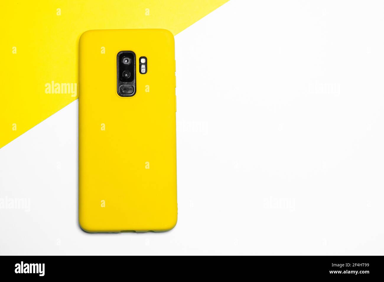 A modern yellow mobile phone on a white and yellow background with a ...