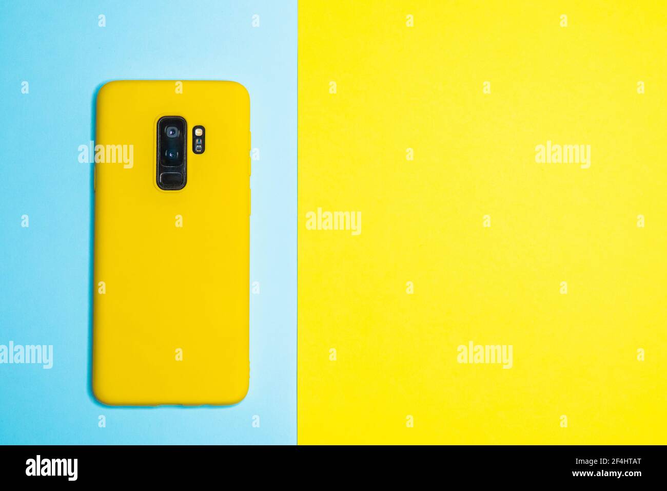 Modern yellow mobile phone on a blue and yellow background with a copy ...
