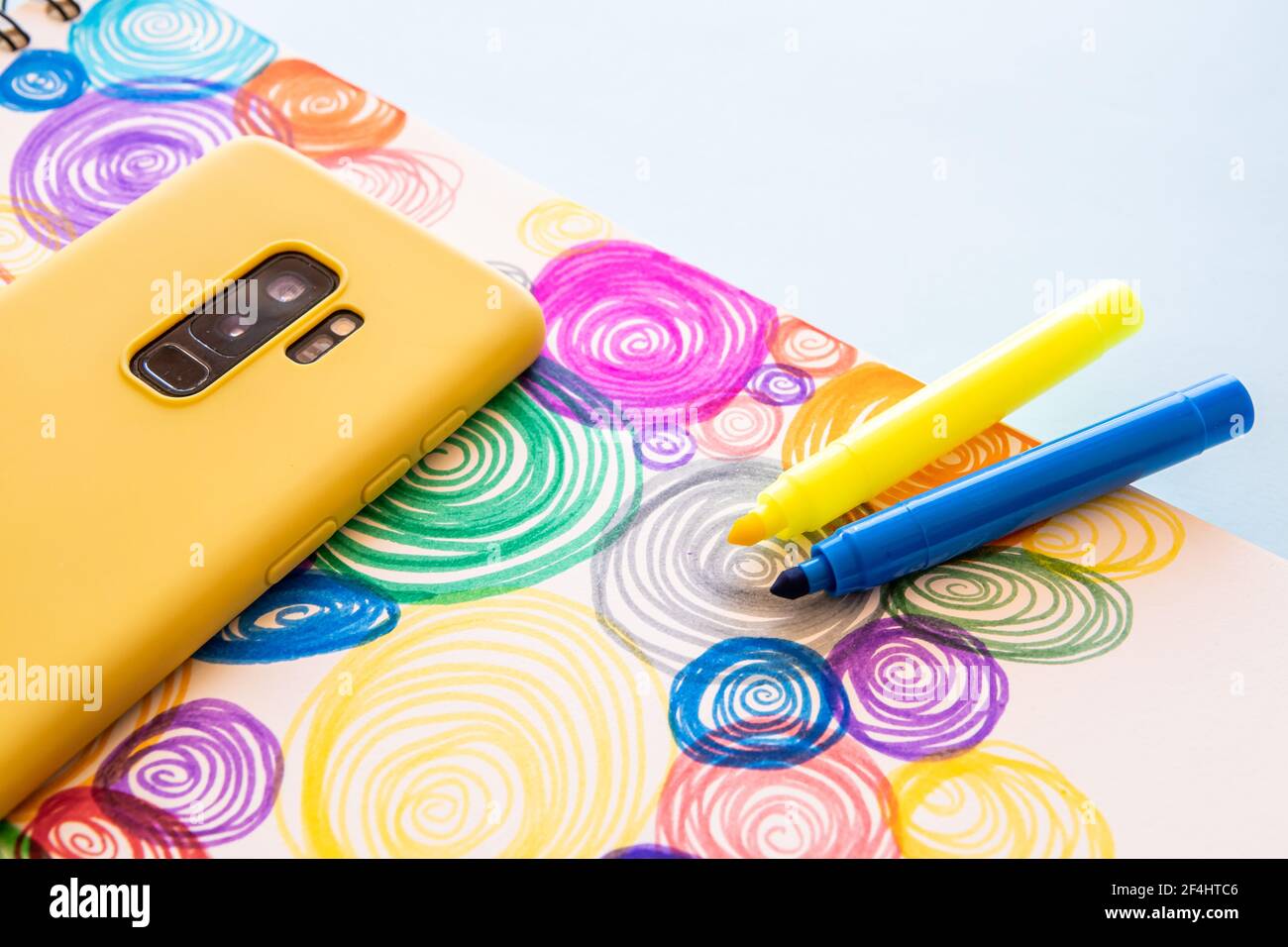 Modern yellow mobile phone on a drawing of colorful spirals next to ...