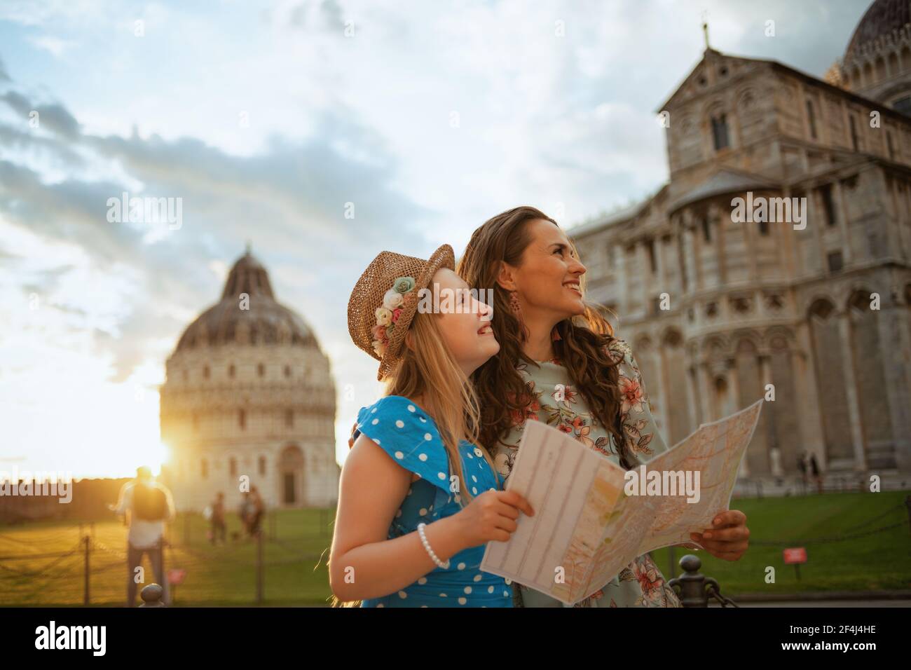 happy elegant mother and child with map sightseeing near Duomo di Pisa ...