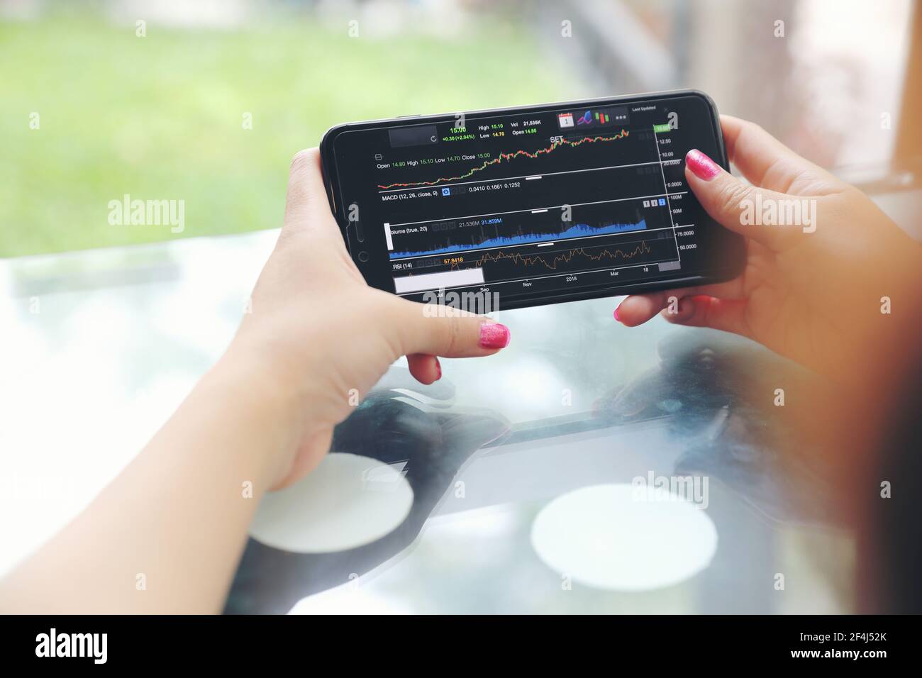 Female hand with smartphone trading stock online in coffee shop ...