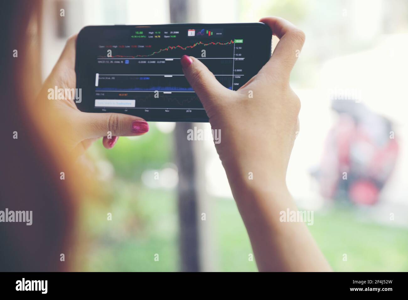 Female hand with smartphone trading stock online in coffee shop ...